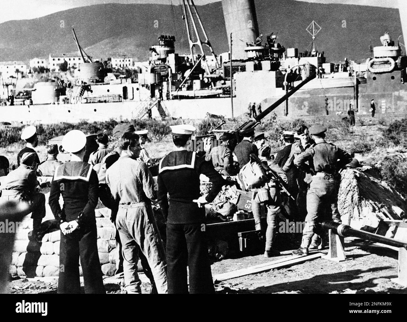 Sailors from the British cruiser H.M.S. Argonaut, (in background), talk ...