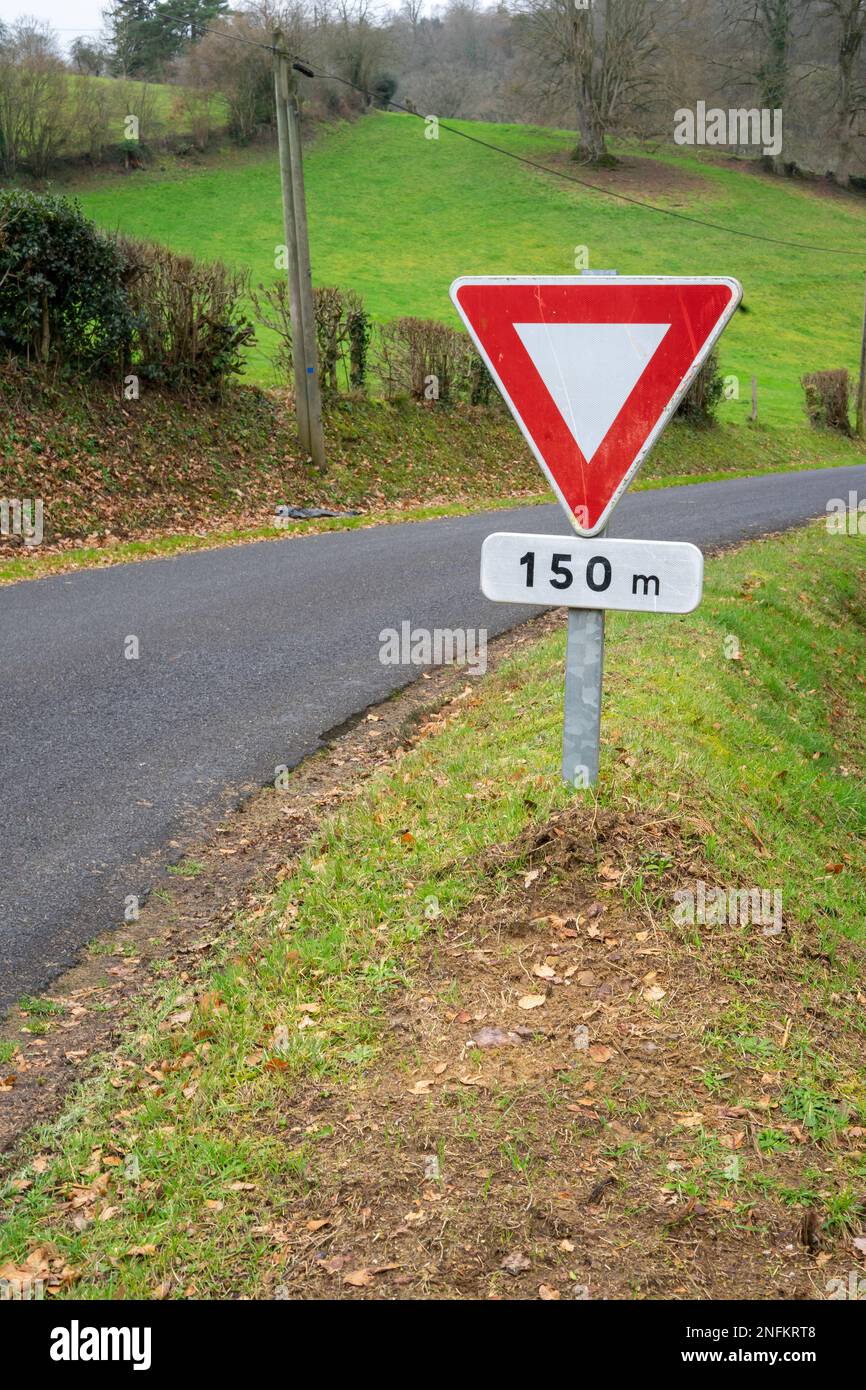 Road in countryside and give way sign. Warning triangle sign. Green ...