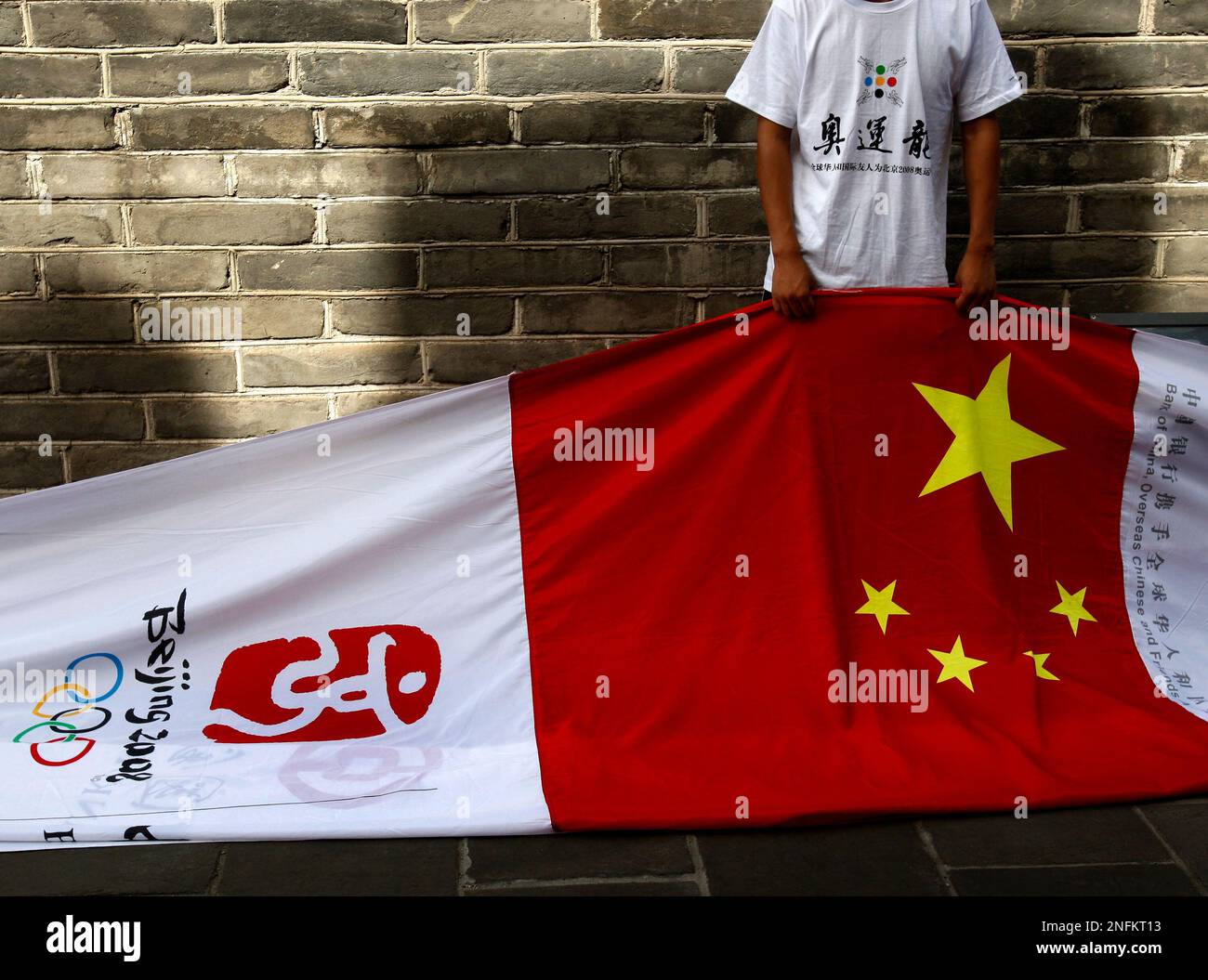 A volunteer holds a scroll called "Olympic Dragon" at the Great Wall of ...