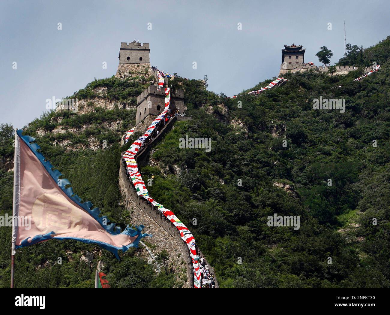 Visitors walk past volunteers unfurling an "Olympic Dragon" scroll at ...