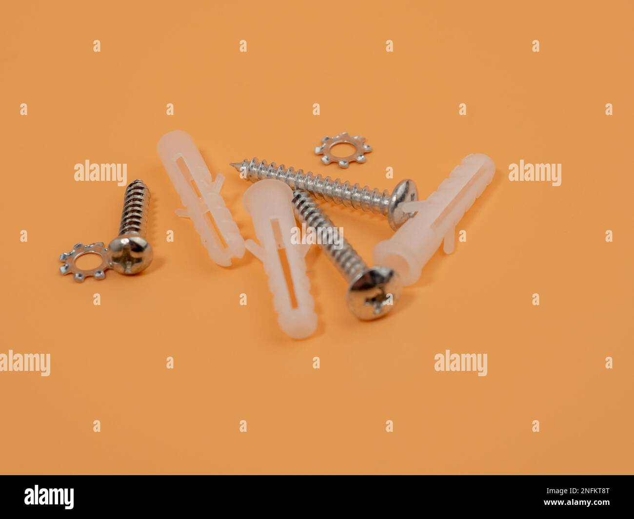 Screws and plastic dowels on an orange background. Bolts and dowels ...