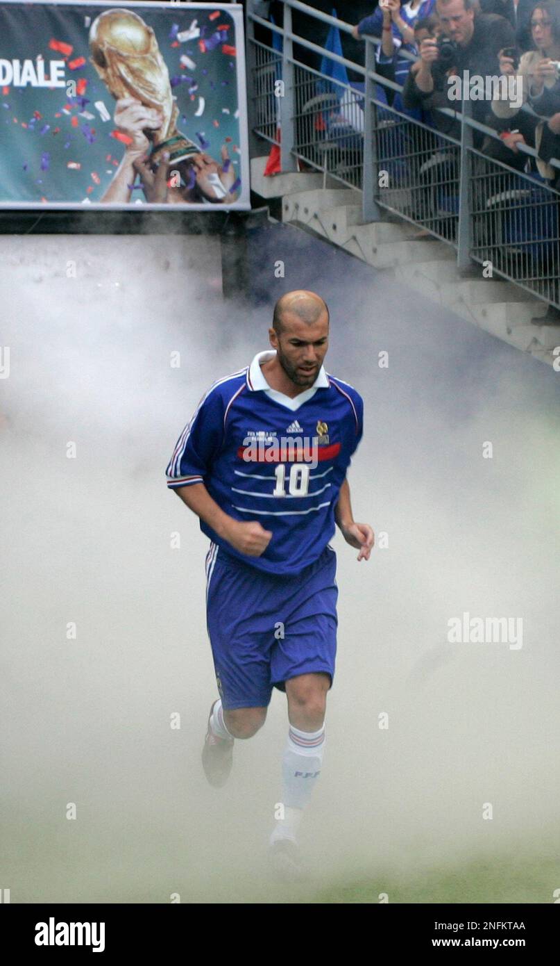 France's Zinedine Zidane runs out the smoke as he enters in the field ...