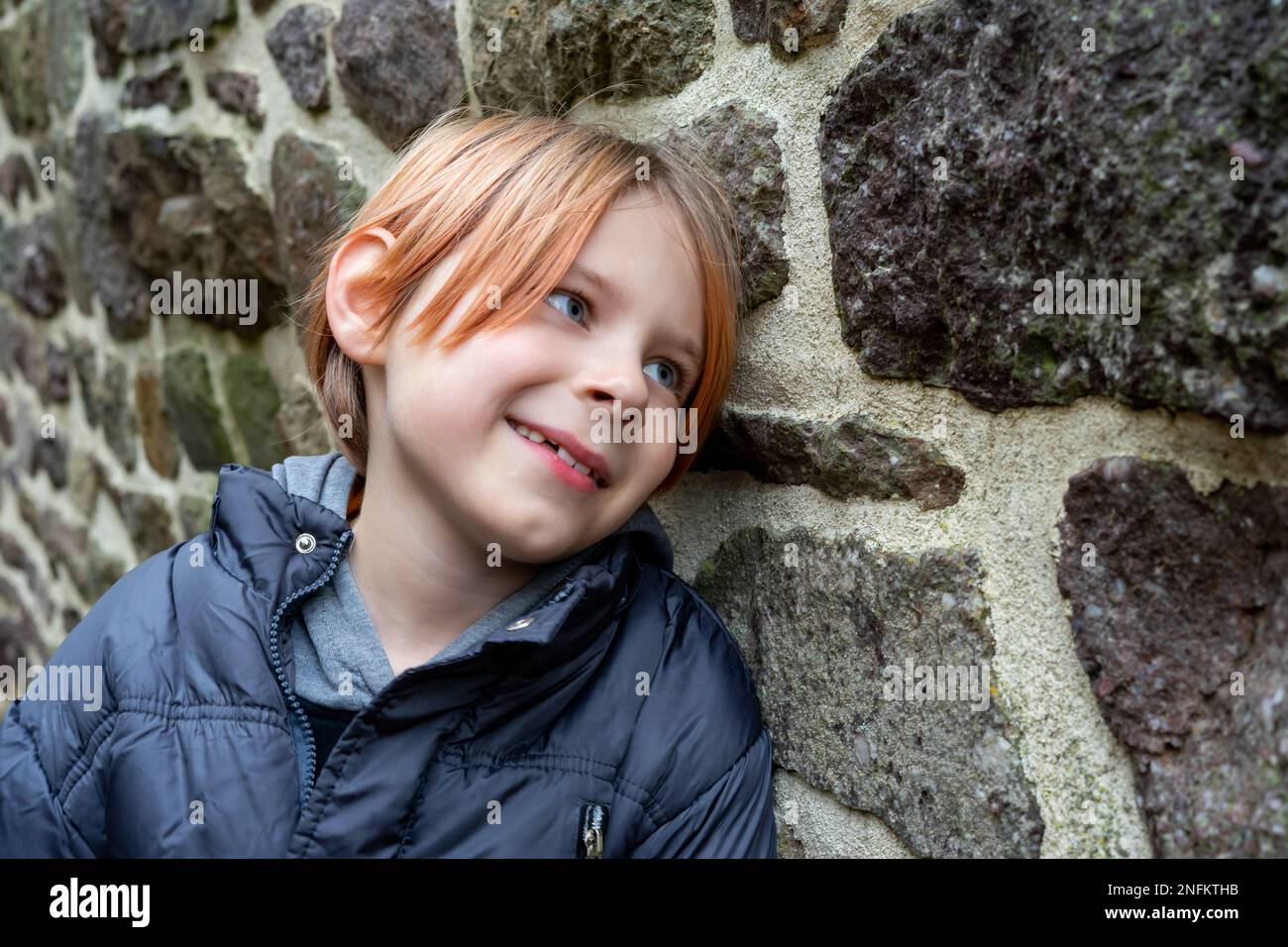 Smiling contented boy near the stone wall. A boy of nine and ten years ...