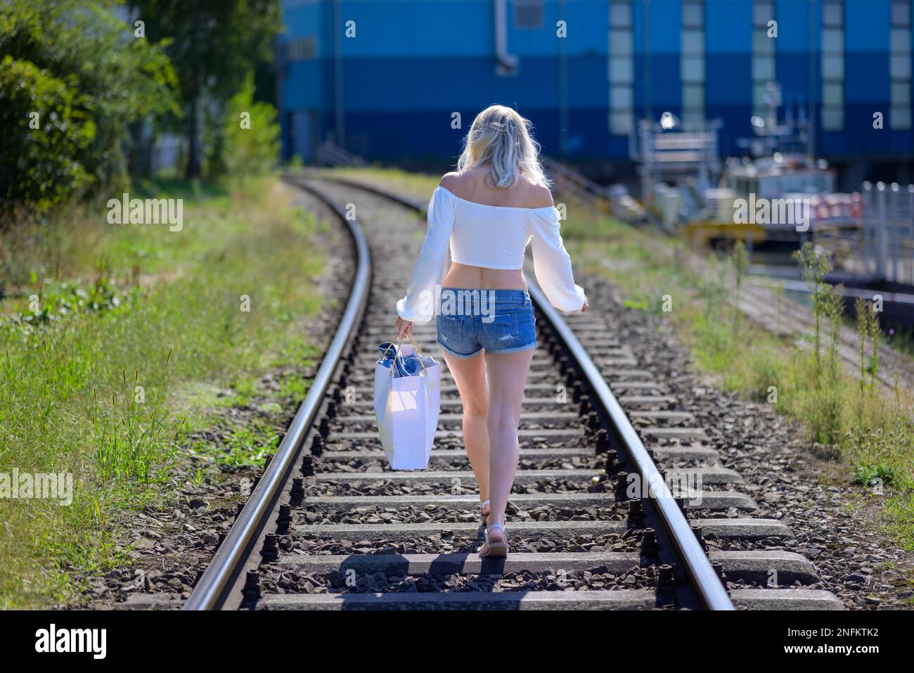 Back view of a blond woman with a white blouse and short jeans and a ...