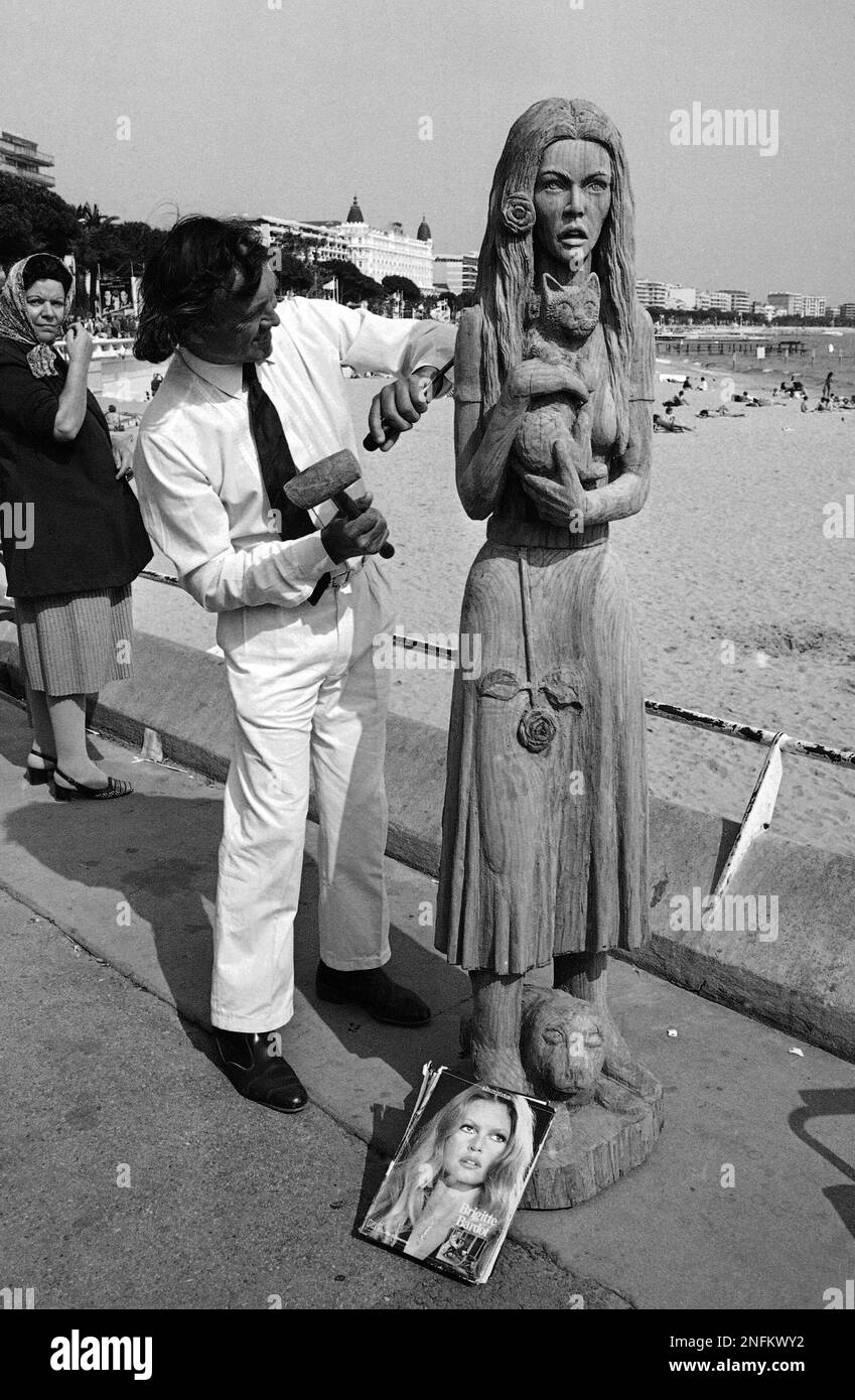An unidentified French sculptor chips away at wooden statue of actress ...
