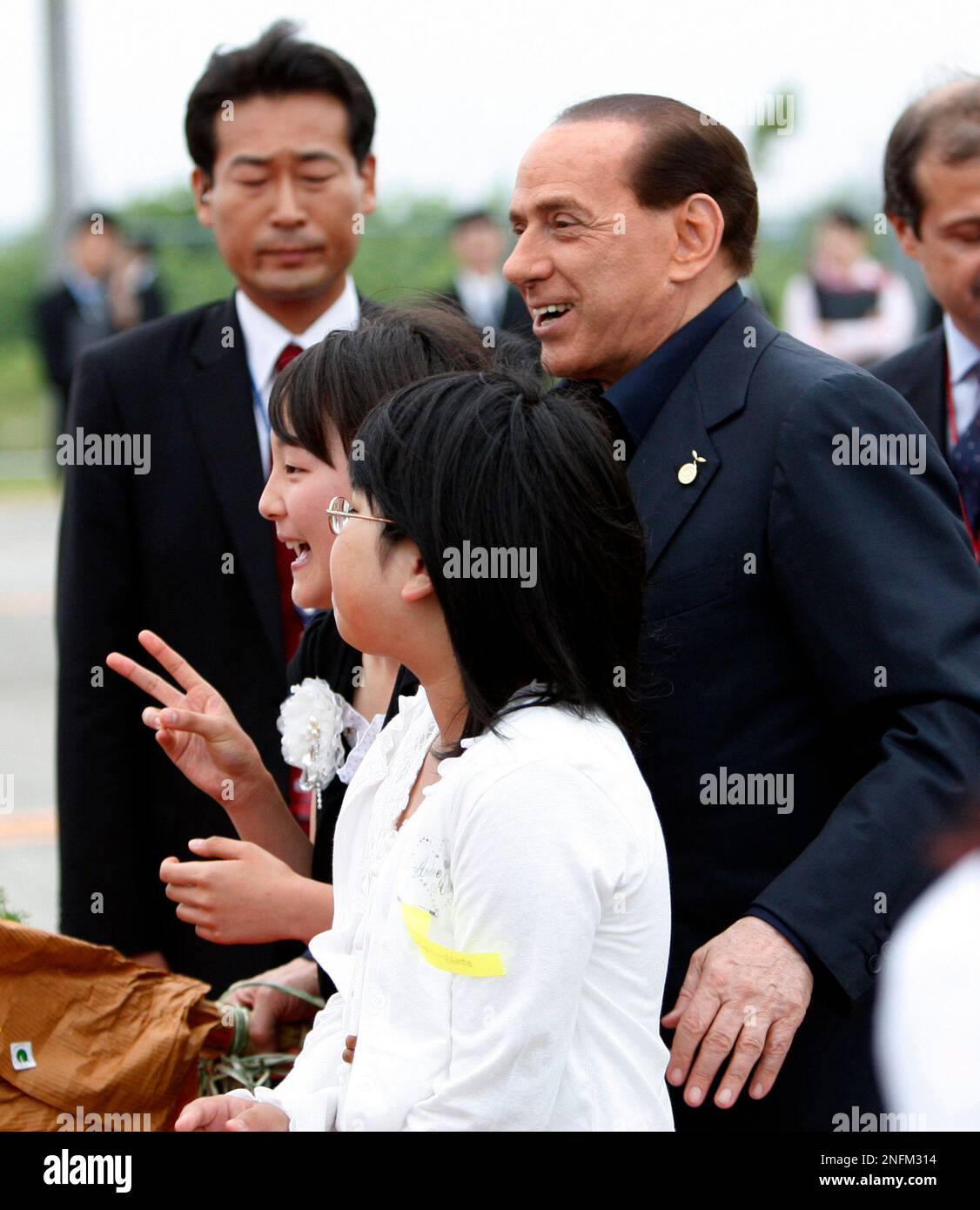 Italy's Prime Minister Silvio Berlusconi walks with Japanese girls upon ...