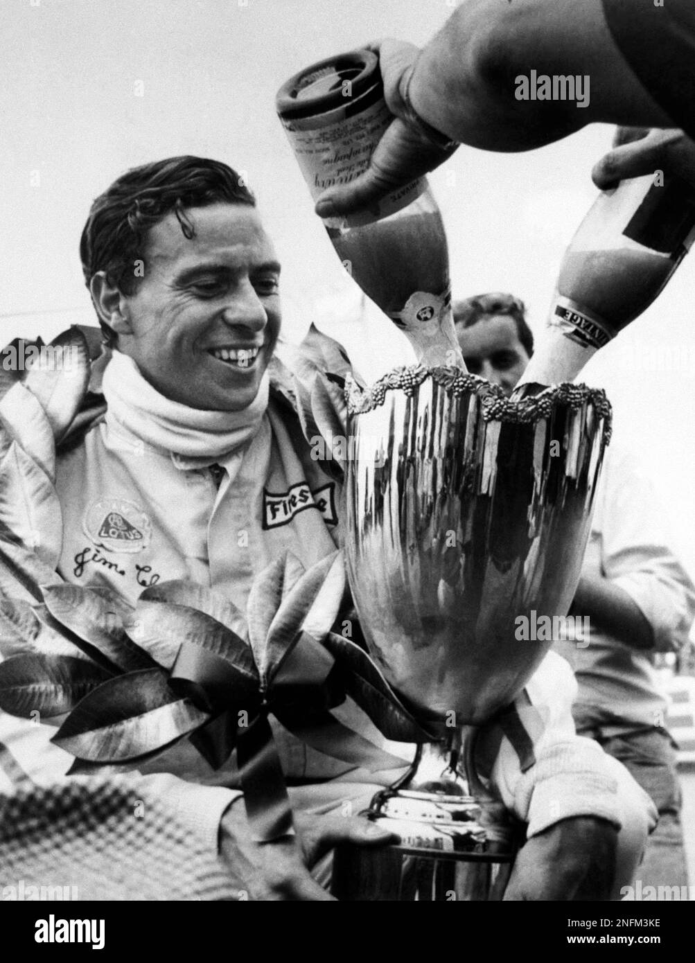 Jim Clark of Scotland, holding the winners trophy watches as champagne ...