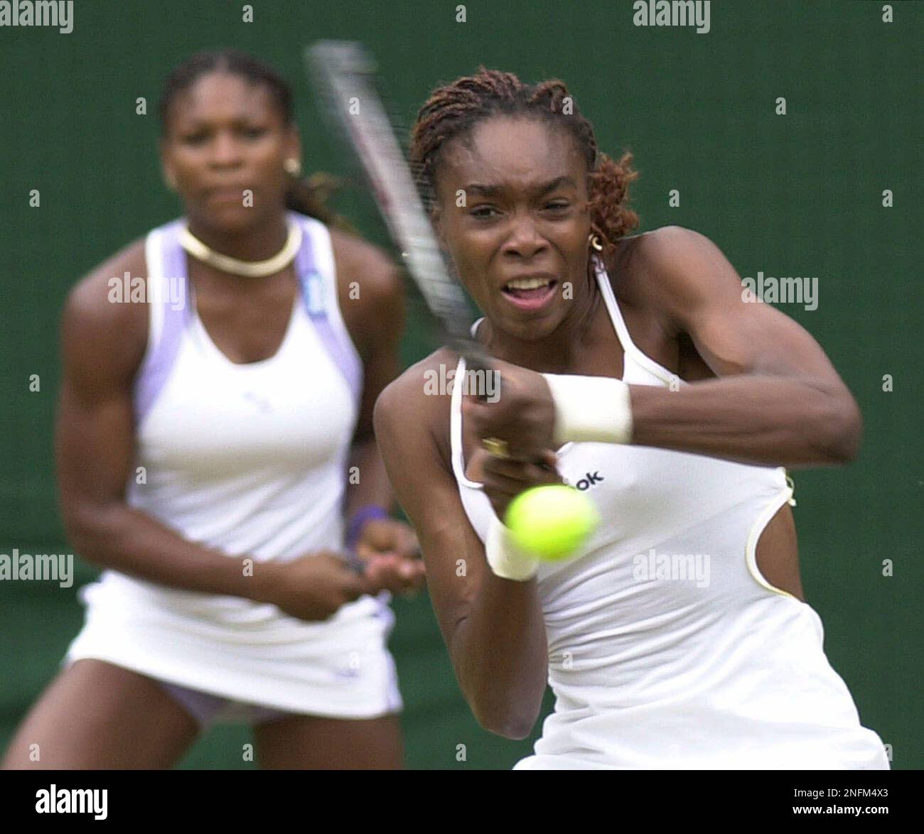 Venus Williams returns, as sister Serena looks on during the Women's ...