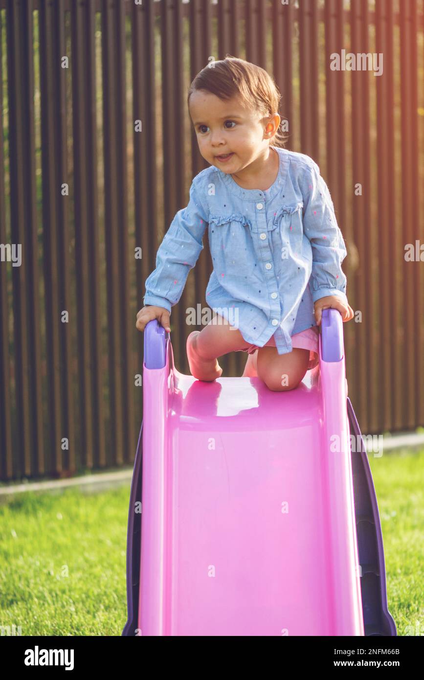 Little and cute girl play on slide and make a grimace while she play ...