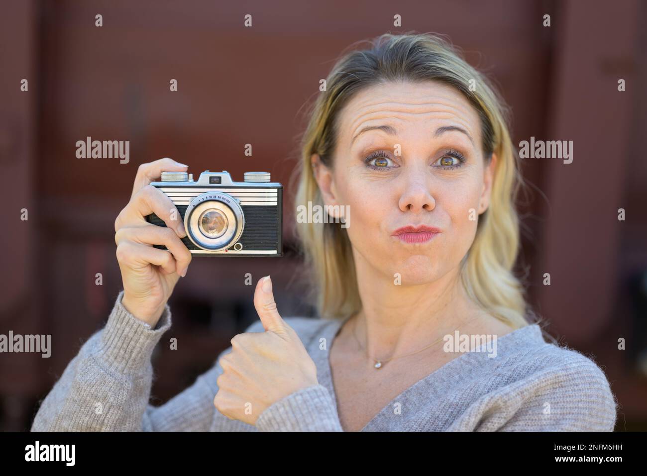 Funny middle aged woman with an old camera in her hand giving a thumb ...