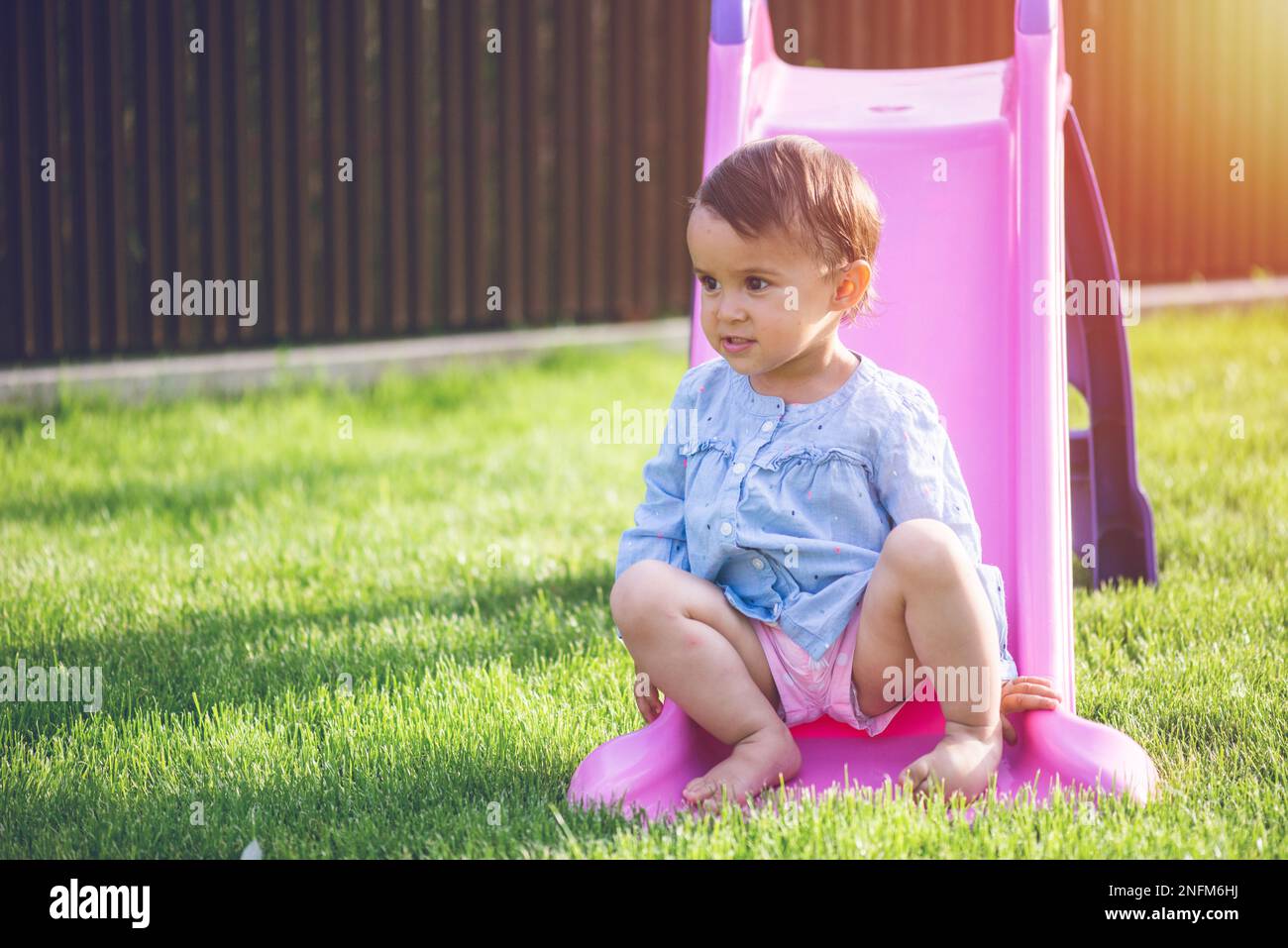 Little and cute girl play on slide and make a grimace while she play ...