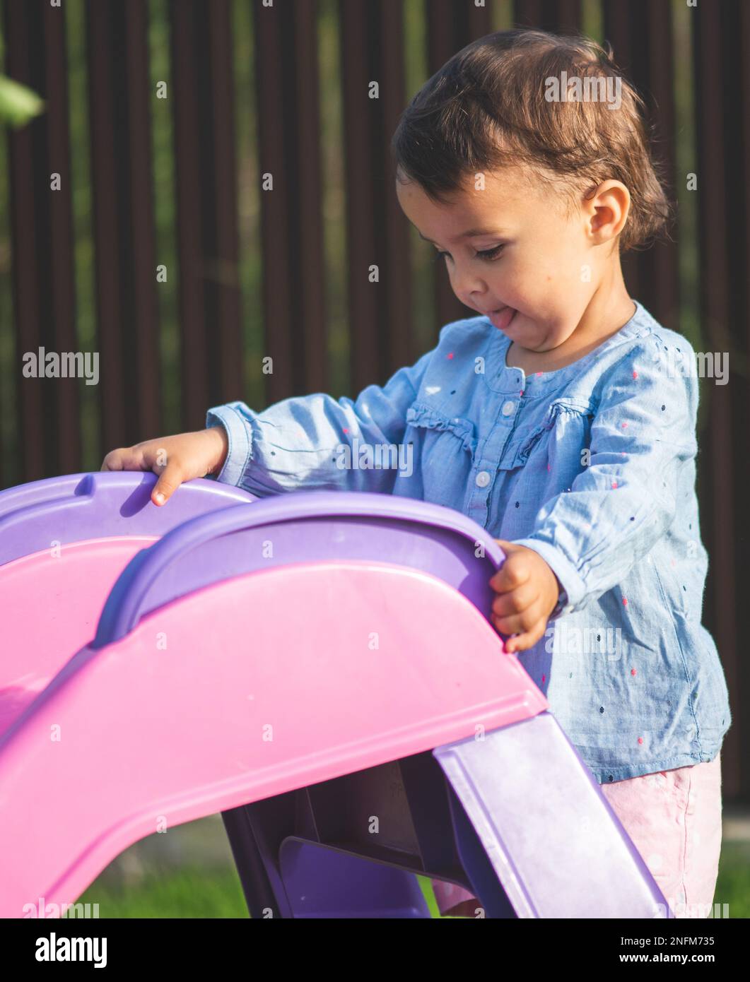 Little and cute girl play on slide and make a grimace while she play ...