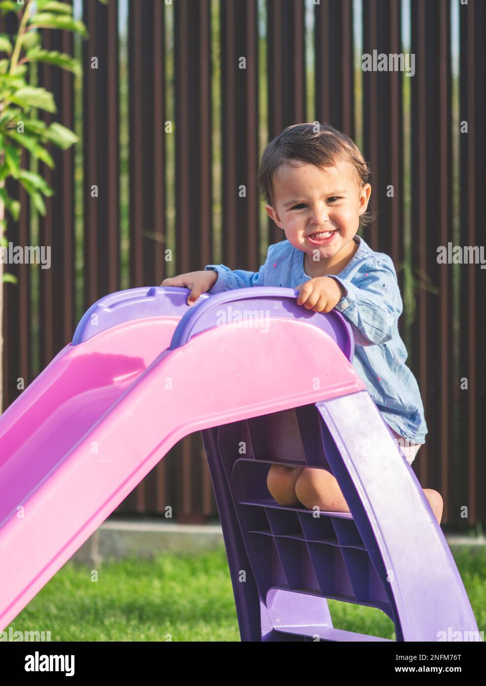 Little and cute girl play on slide and make a grimace while she play ...