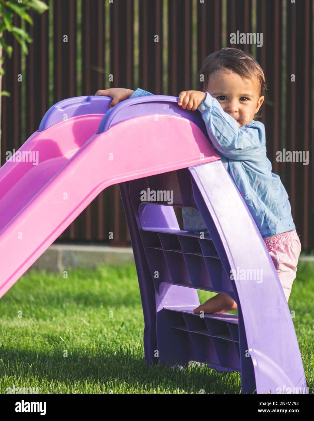 Little and cute girl play on slide and make a grimace while she play ...