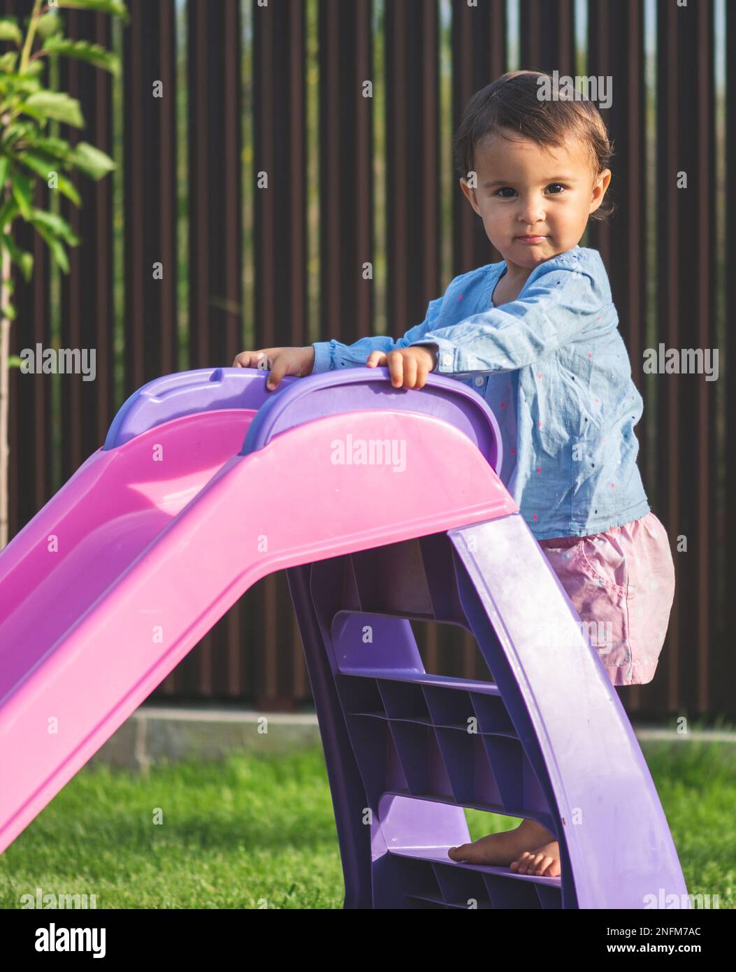 Little and cute girl play on slide and make a grimace while she play ...