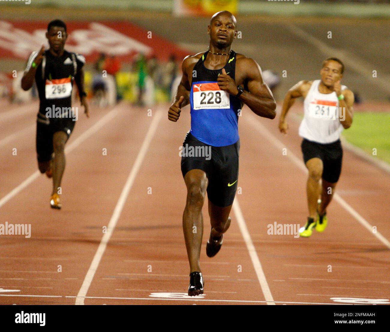 Asafa Powell, center, wins his heat, in front of Dwight Williams, left ...