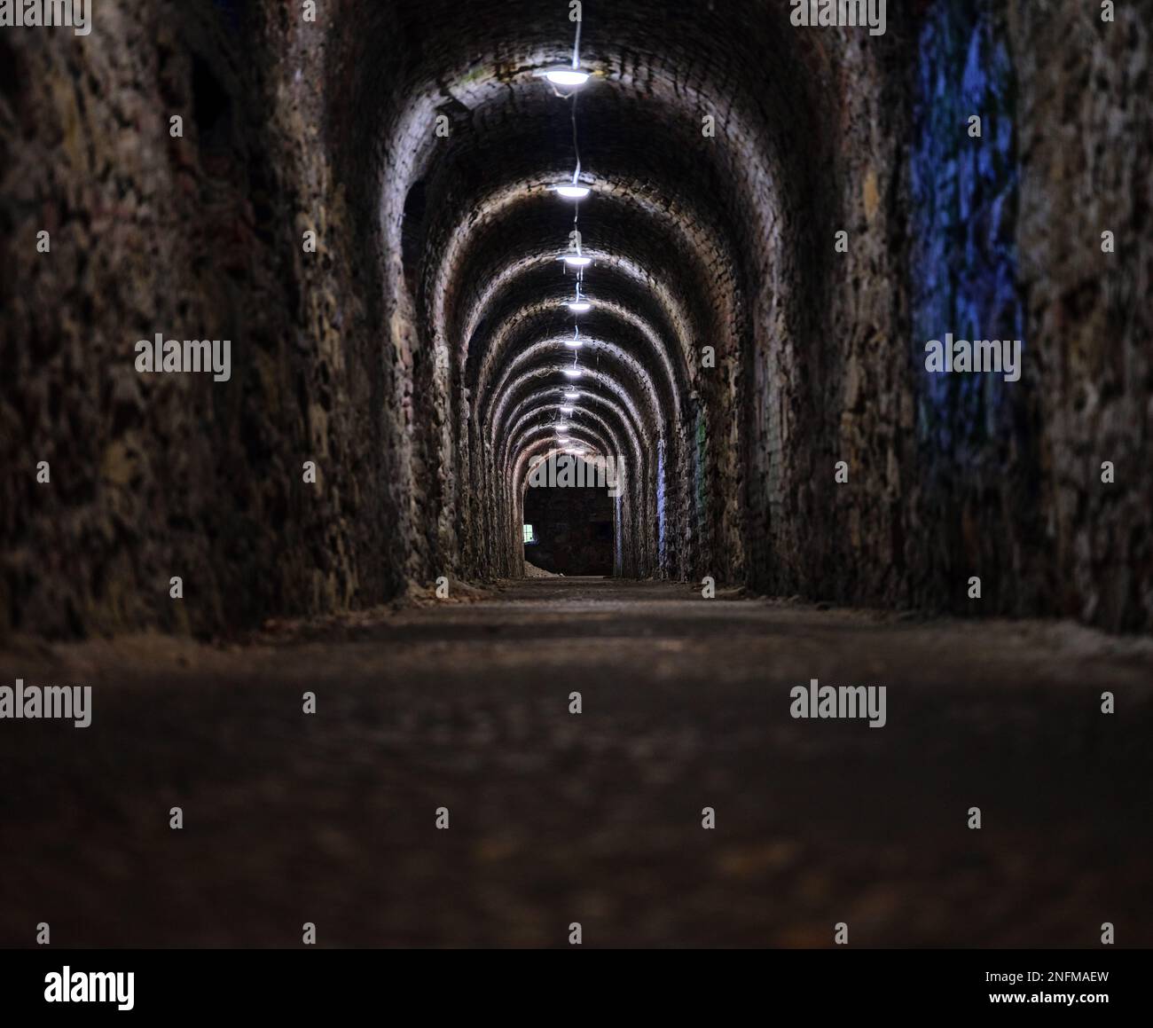 The underground stony passage with lights on the ceiling Stock Photo ...