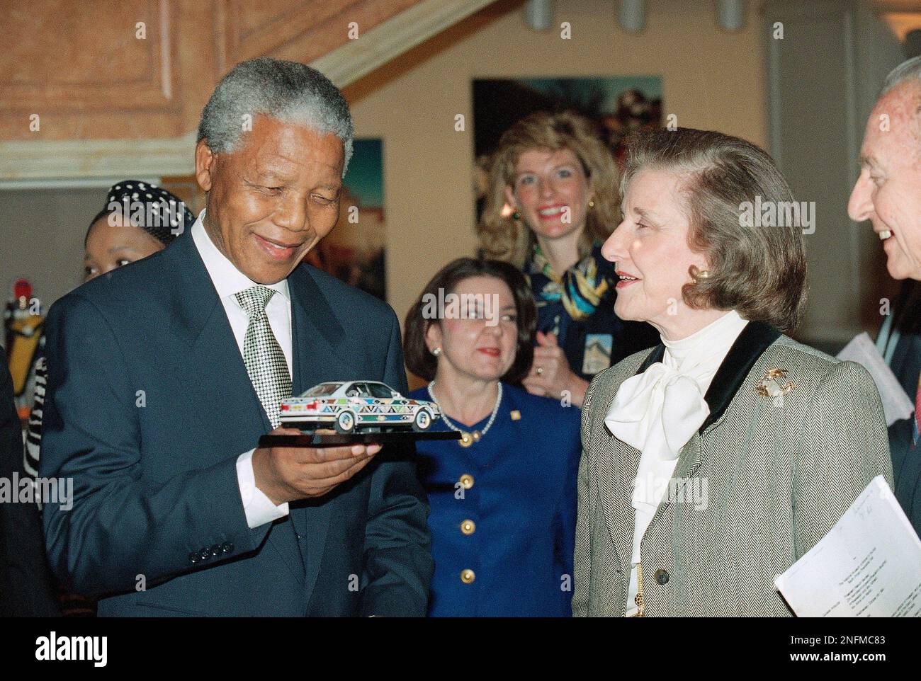 South African President Nelson Mandela holds a model of a painted BMW ...