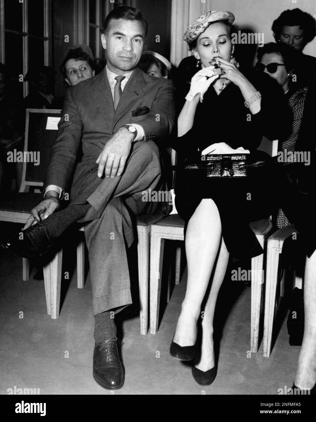 Zsa Zsa Gabor, lights her cigarette with a jeweled studded lighter ...