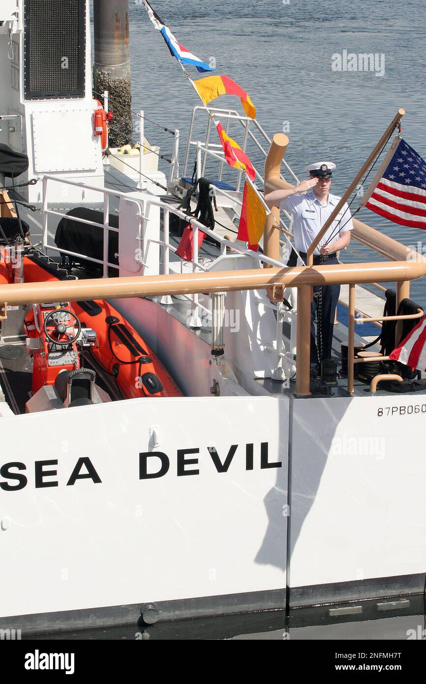 EM2 Scott Miller of the U.S. Coast Guard Cutter salutes the flag as he ...