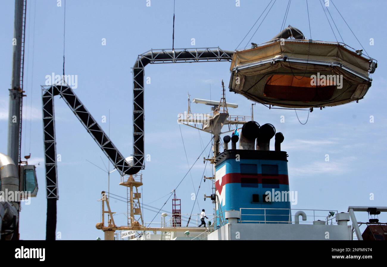 A crane lowera a large 'bonnet" over the funnel of a ship during a ...