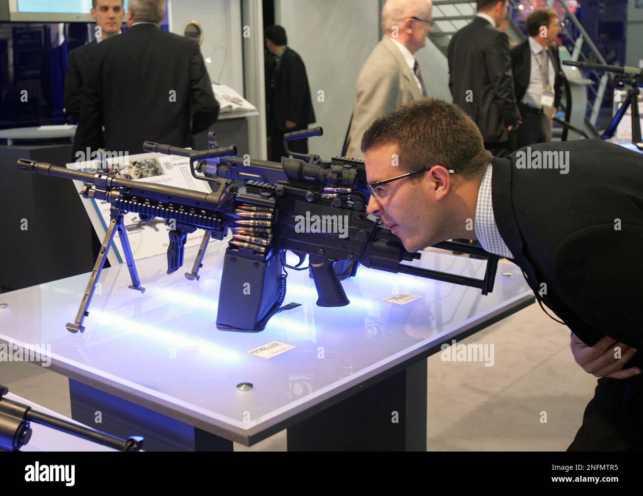 A visitor looks through the sights of a machine gun on display at the ...