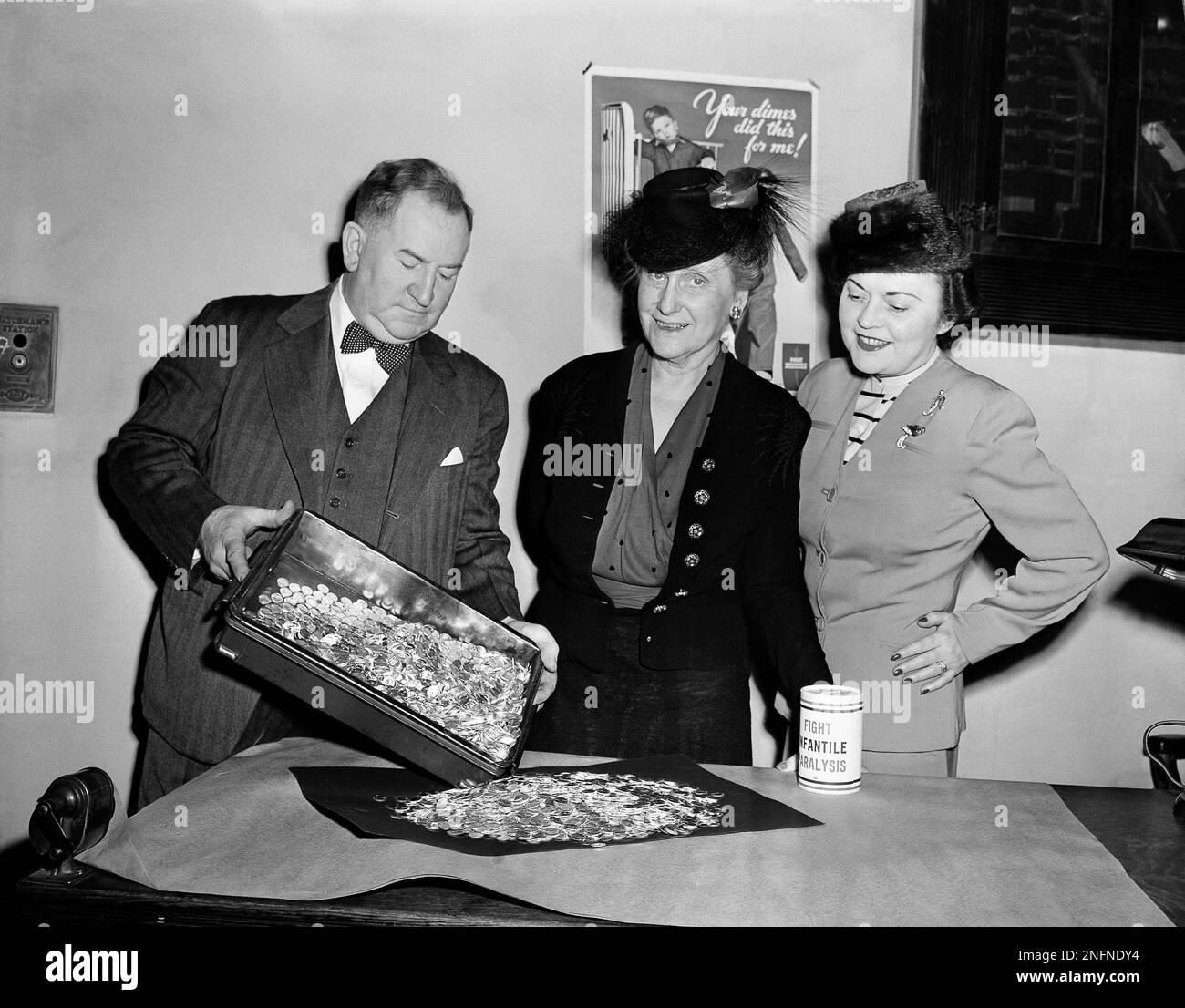 Superintendent Edward Dressel pouring dimes on table with director ...