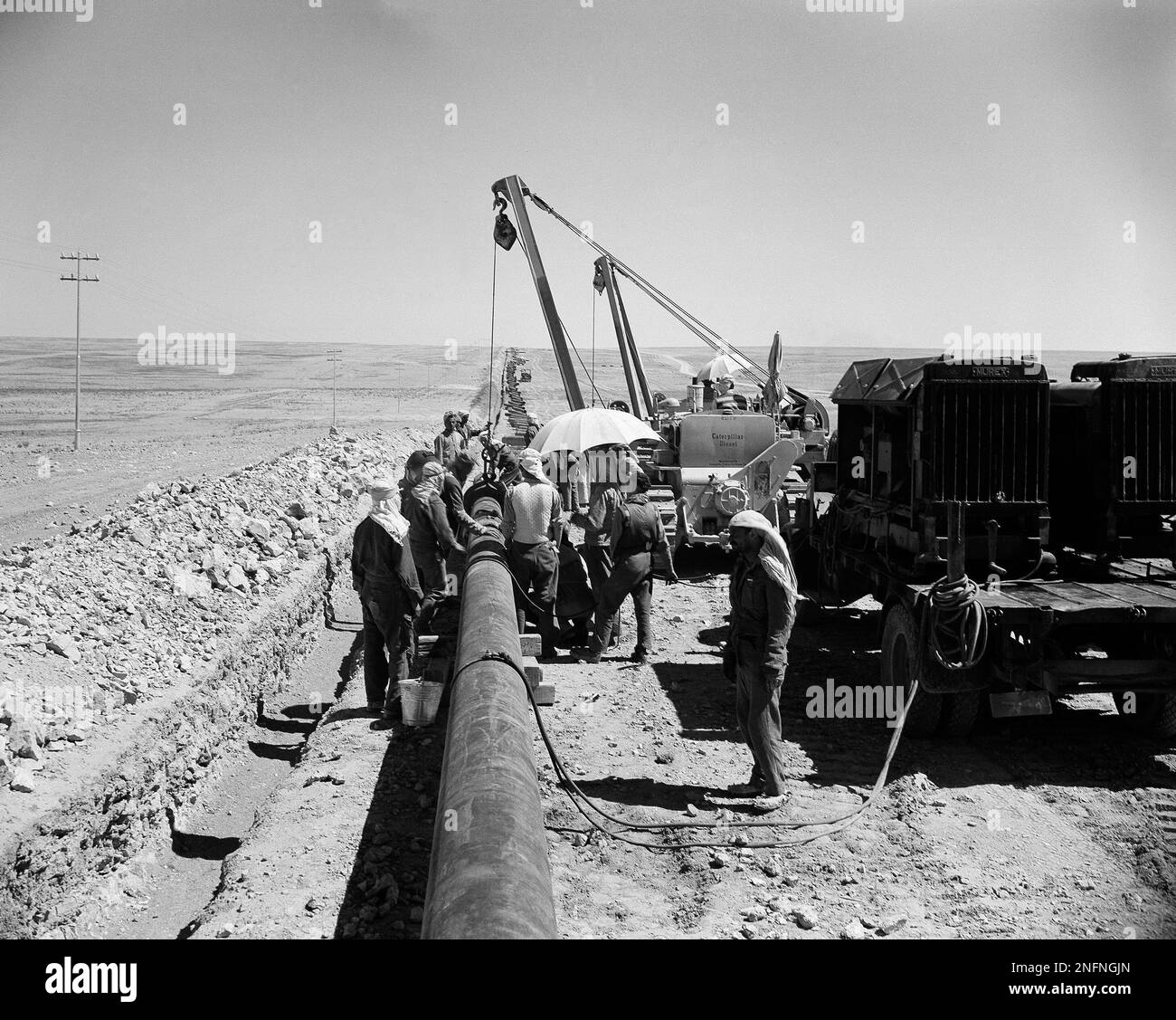 Pipes being held together by two American tractors while the first weld ...