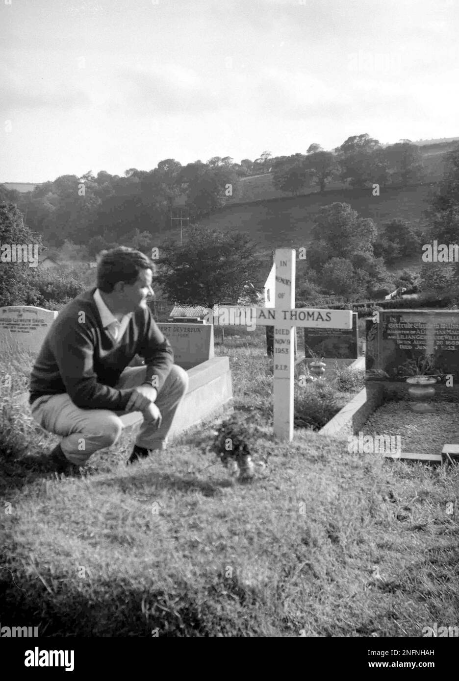 A visitor looks at the simple wooden cross that marks the grave of ...