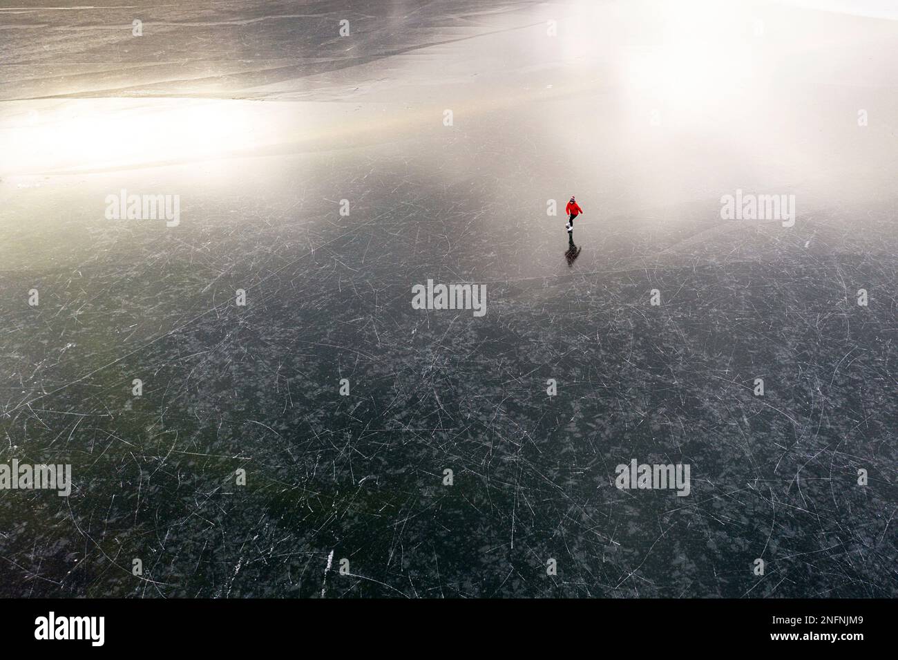 Aerial view of a Woman in red ice skating in nature on a beautiful ...
