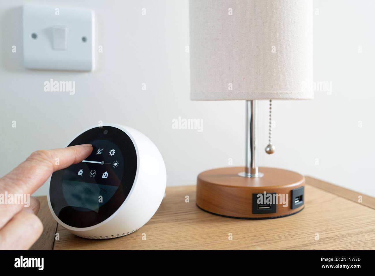 Person seeing setting up his smart home device. Located on a bedside ...