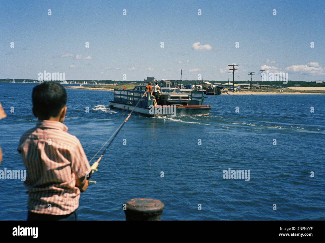 A boy fishes from dock near the ferry landing at Edgartown, Mass. as ...