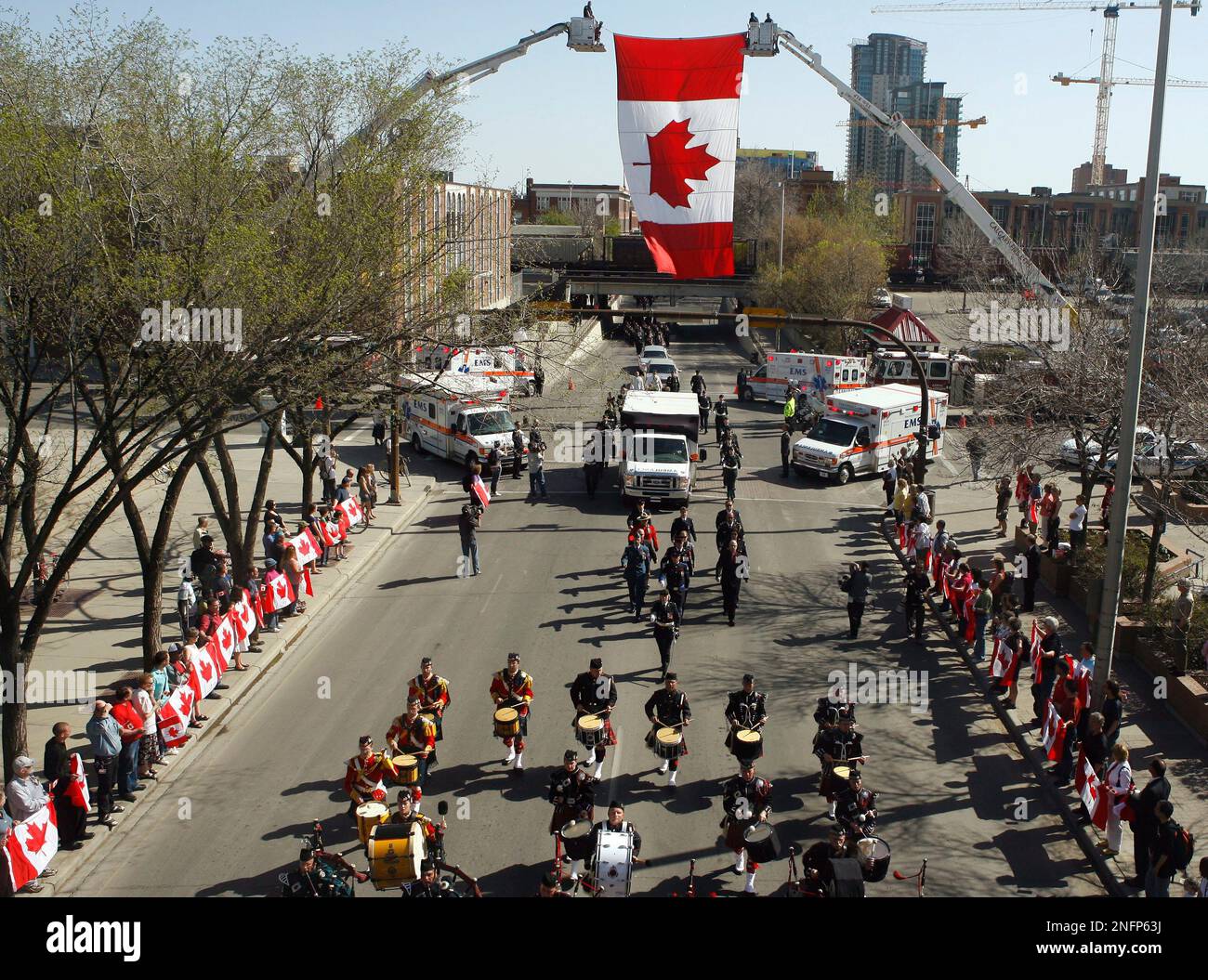 Fire department aerial ladders drap a Canadian flag above the ambulance ...