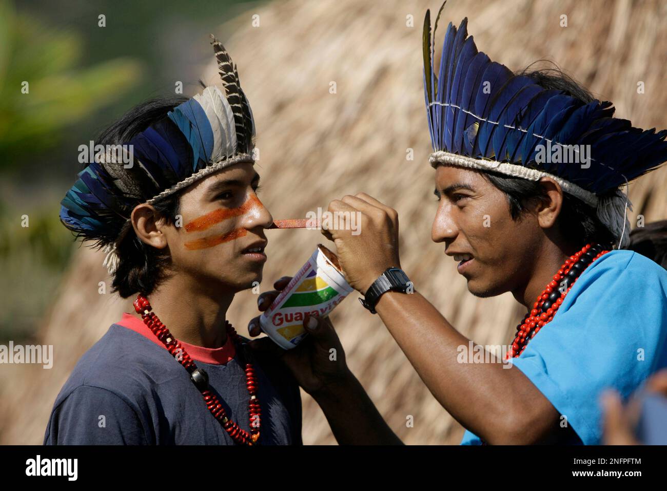 An Indigenous Guarani man has his face painted by a fellow in ...