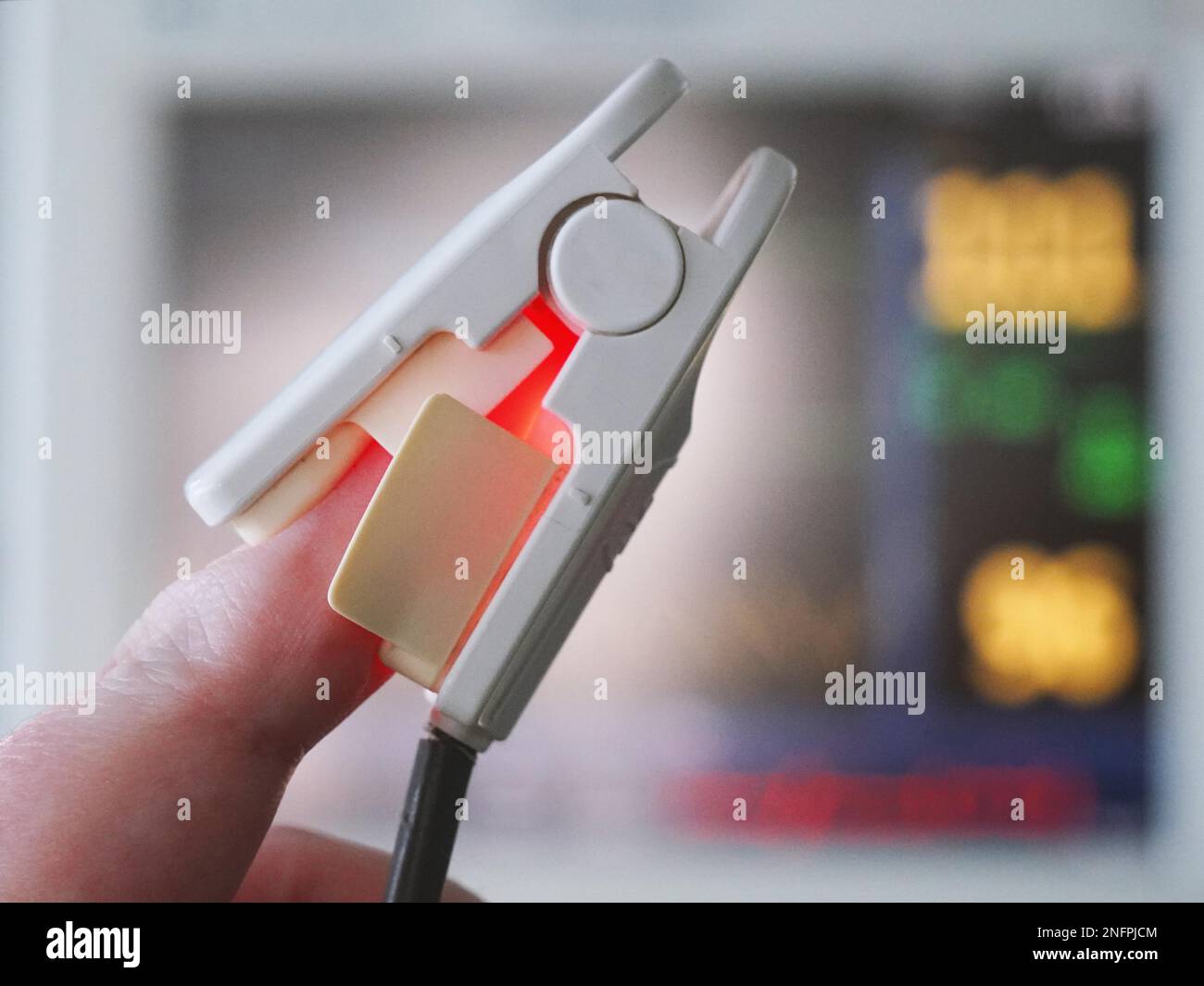 pulse oximeter on hospital patient finger with monitor in background ...