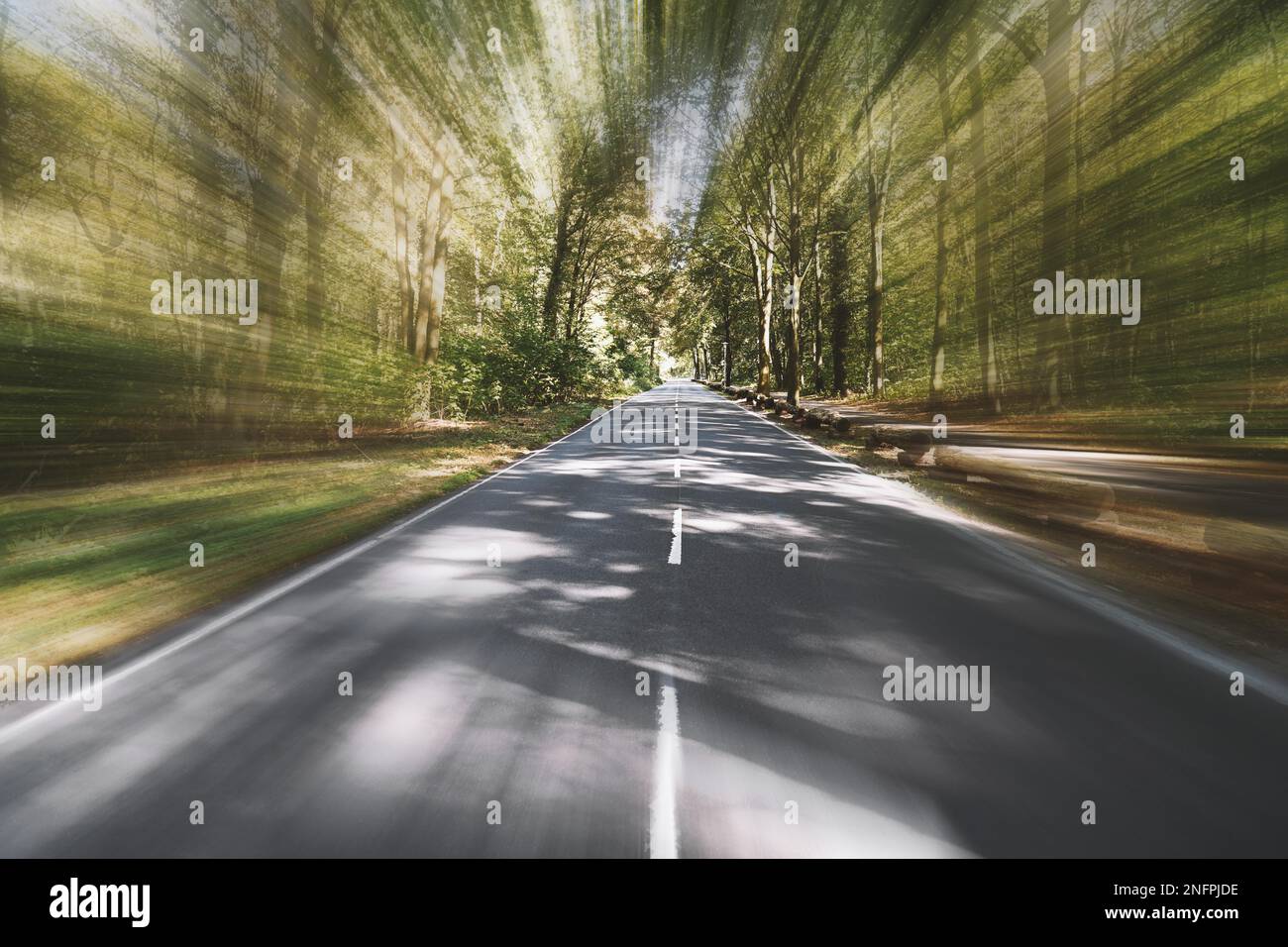 empty two-lane country road through woodland with motion blur speed ...