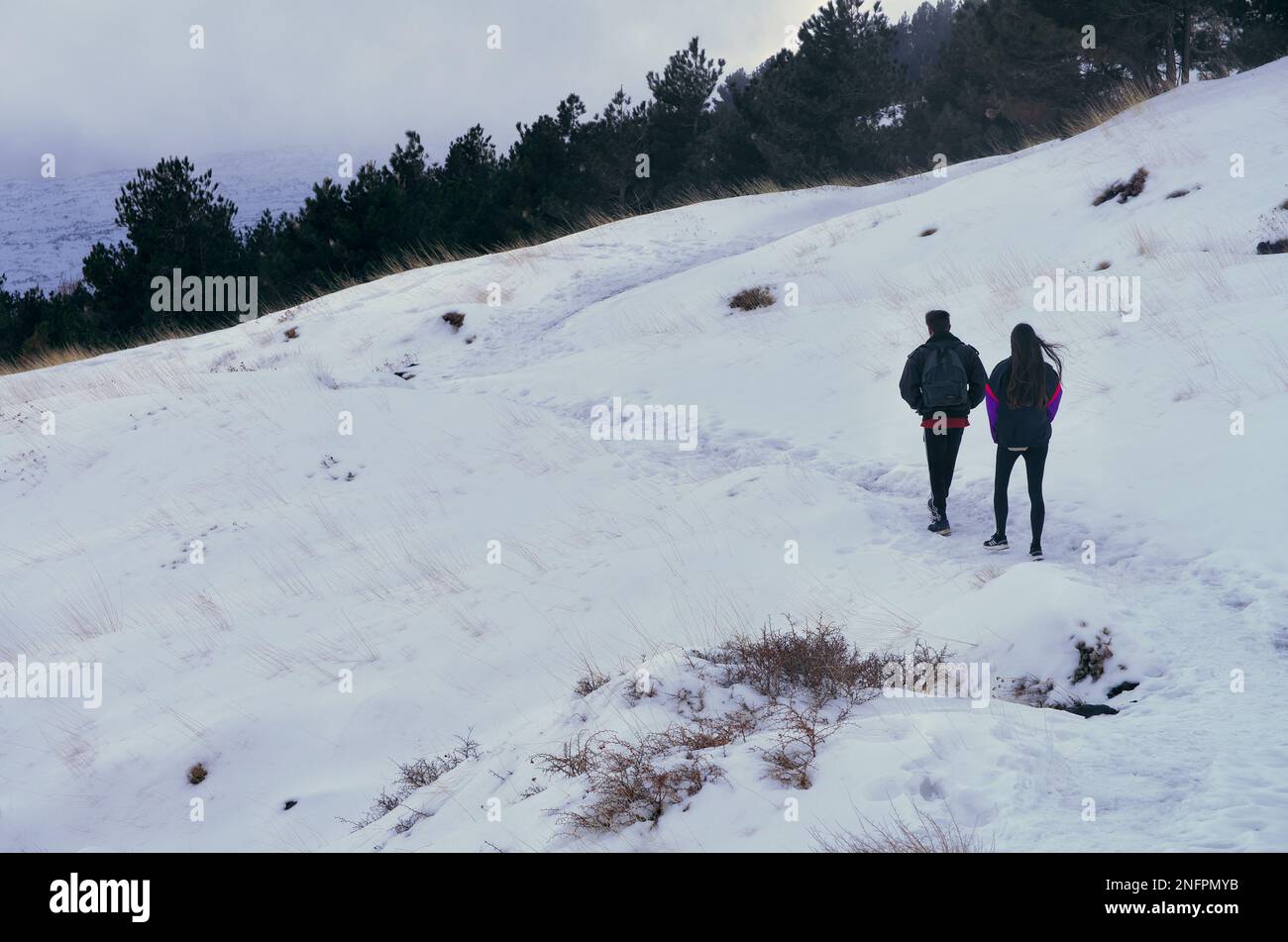 couple walking on snow path from the "Schiena dell'Asino" in Etna ...