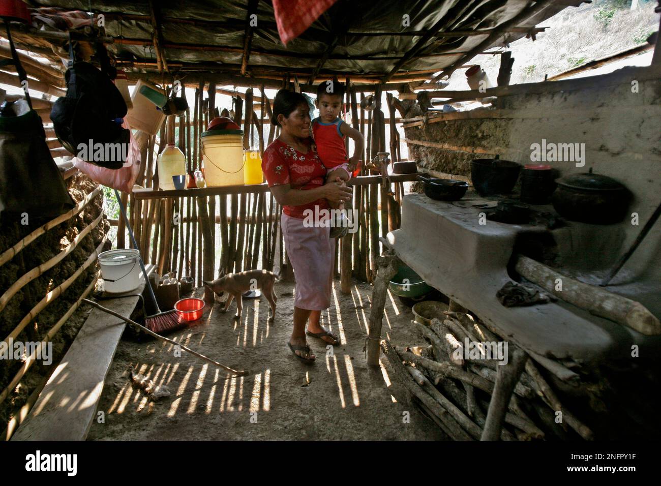 A woman carrying a boy stands at her shack in Telpaneca, northern ...