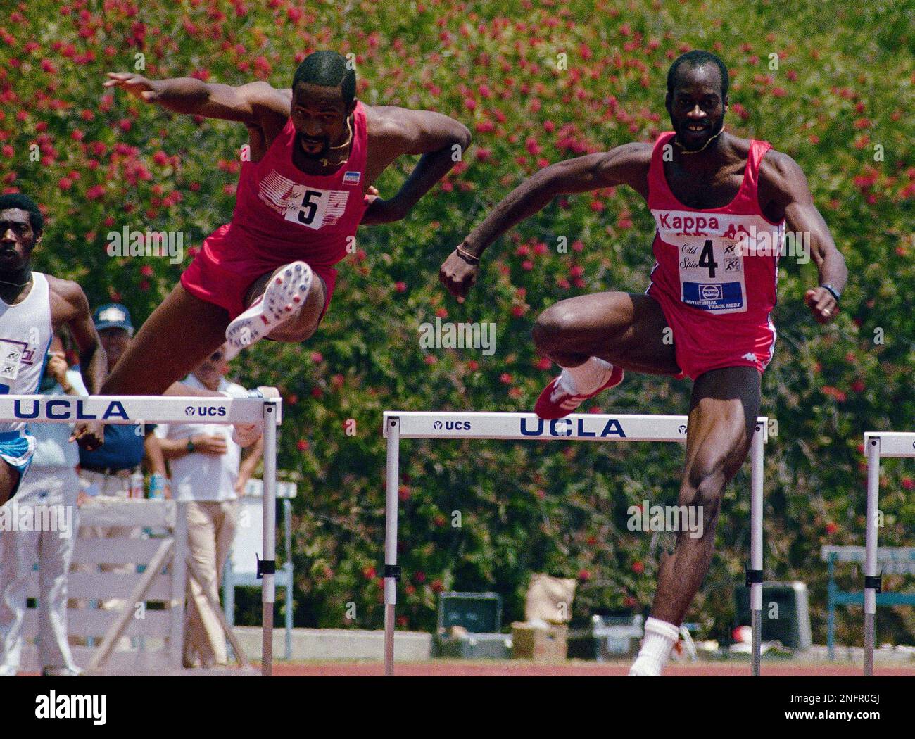 American track and field star Edwin Moses, right, goes over the hurdle ...