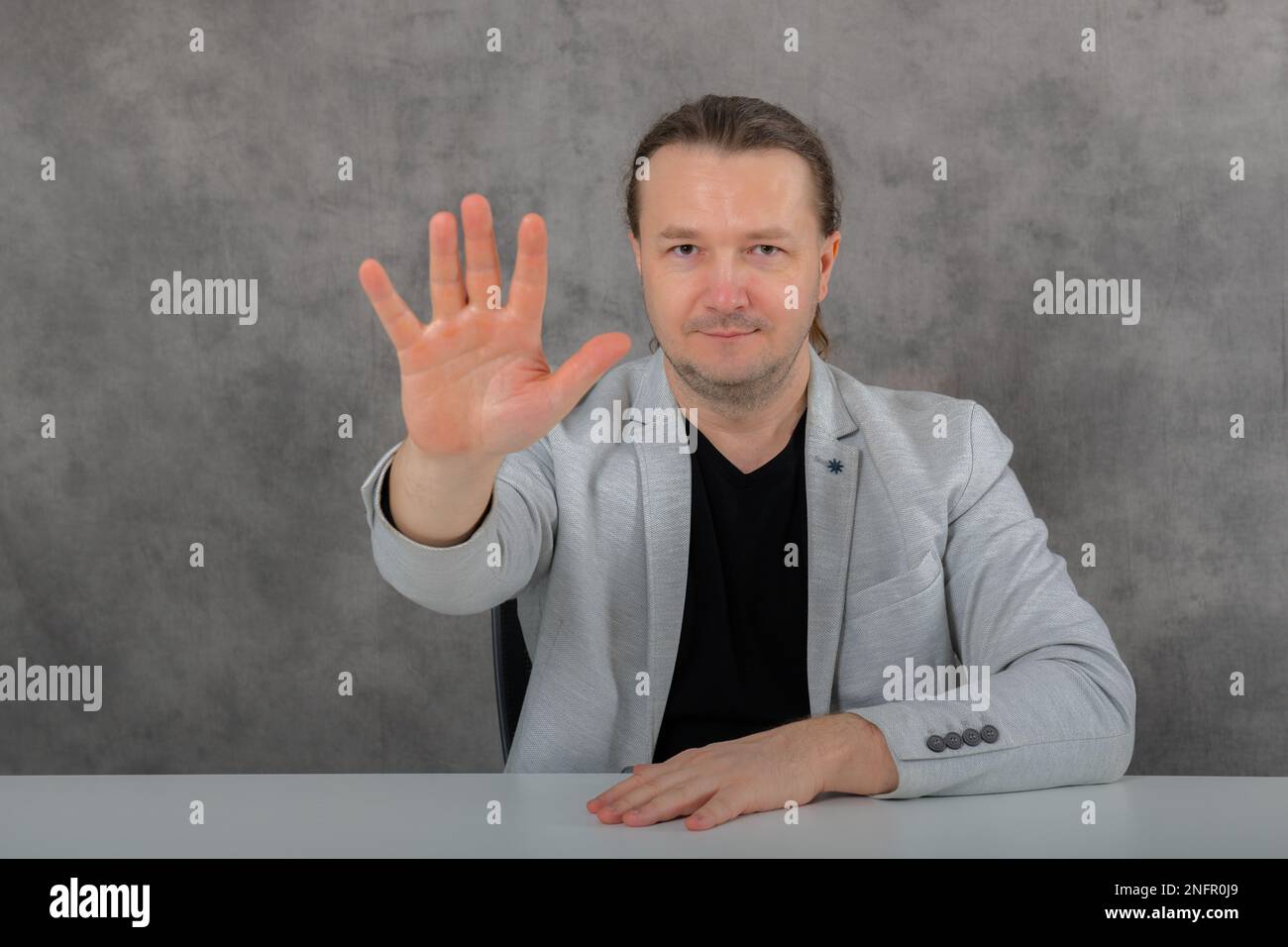 a stop sign is shown by a man in a gray suit Stock Photo - Alamy