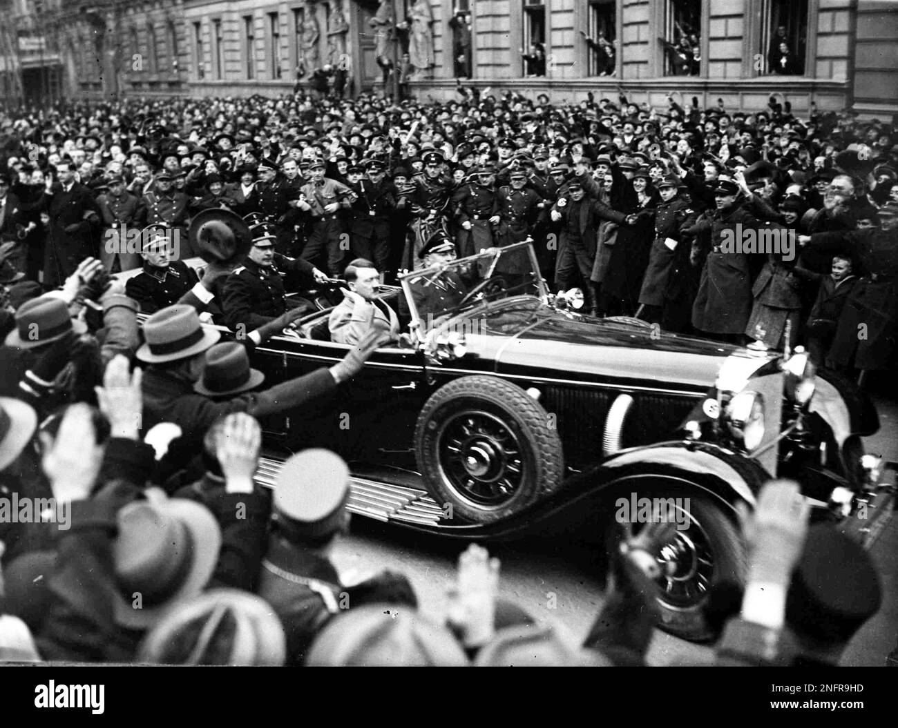 German Chancellor Adolf Hitler salutes as he is driven through a large ...