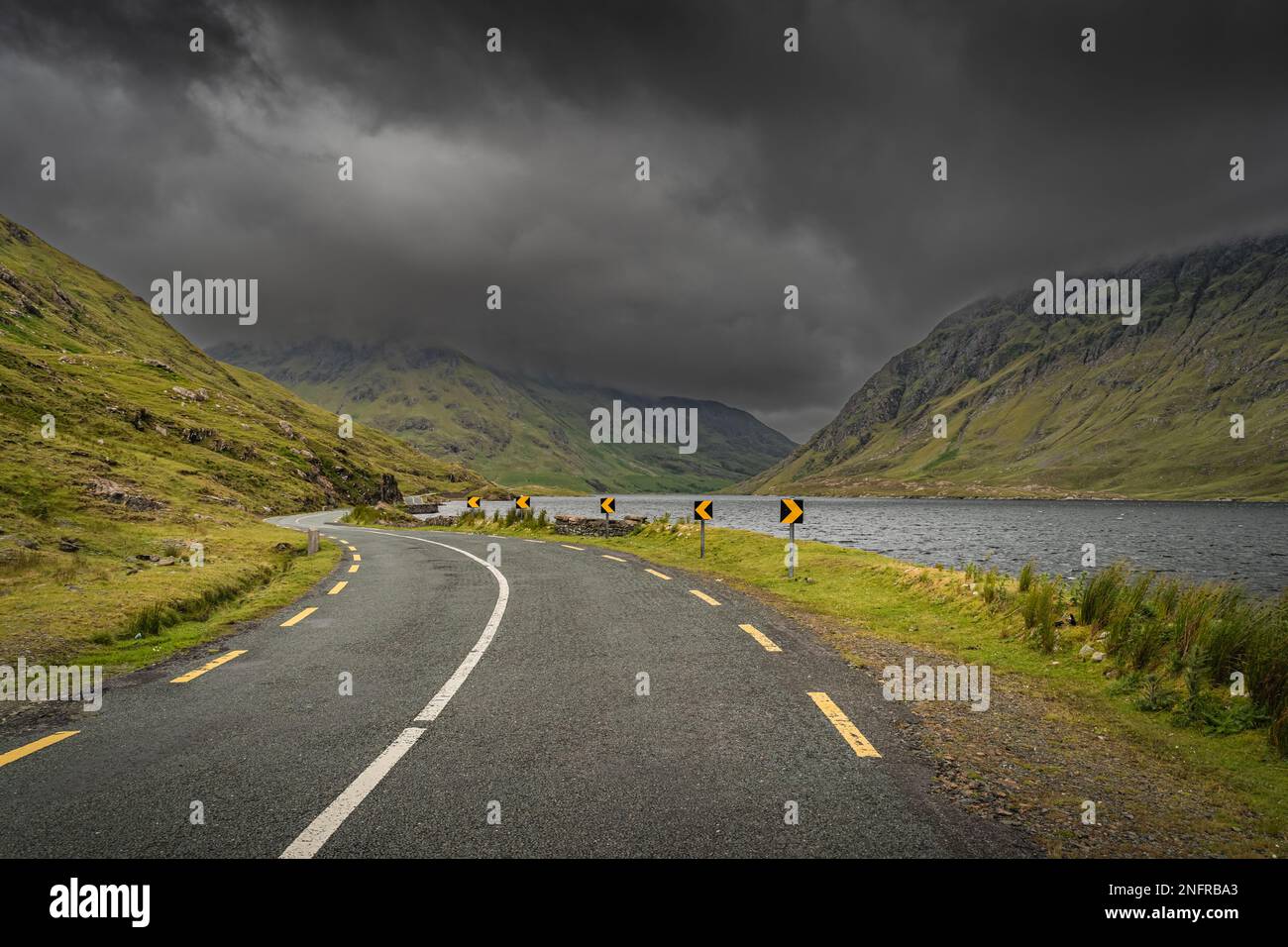 Winding road leading trough Doolough Valley with lake, between ...