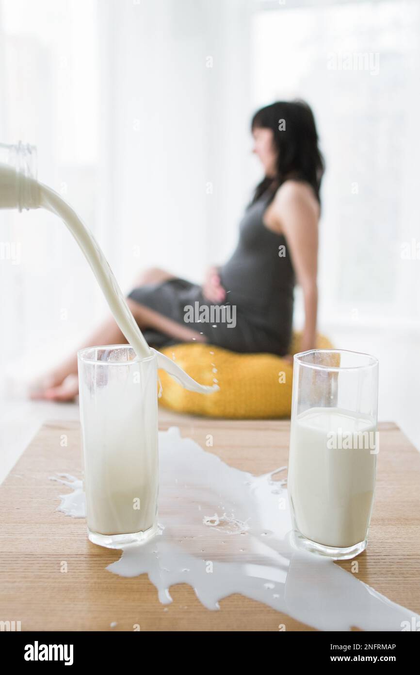 Milk pouring out to glass and spilling on table Stock Photo - Alamy