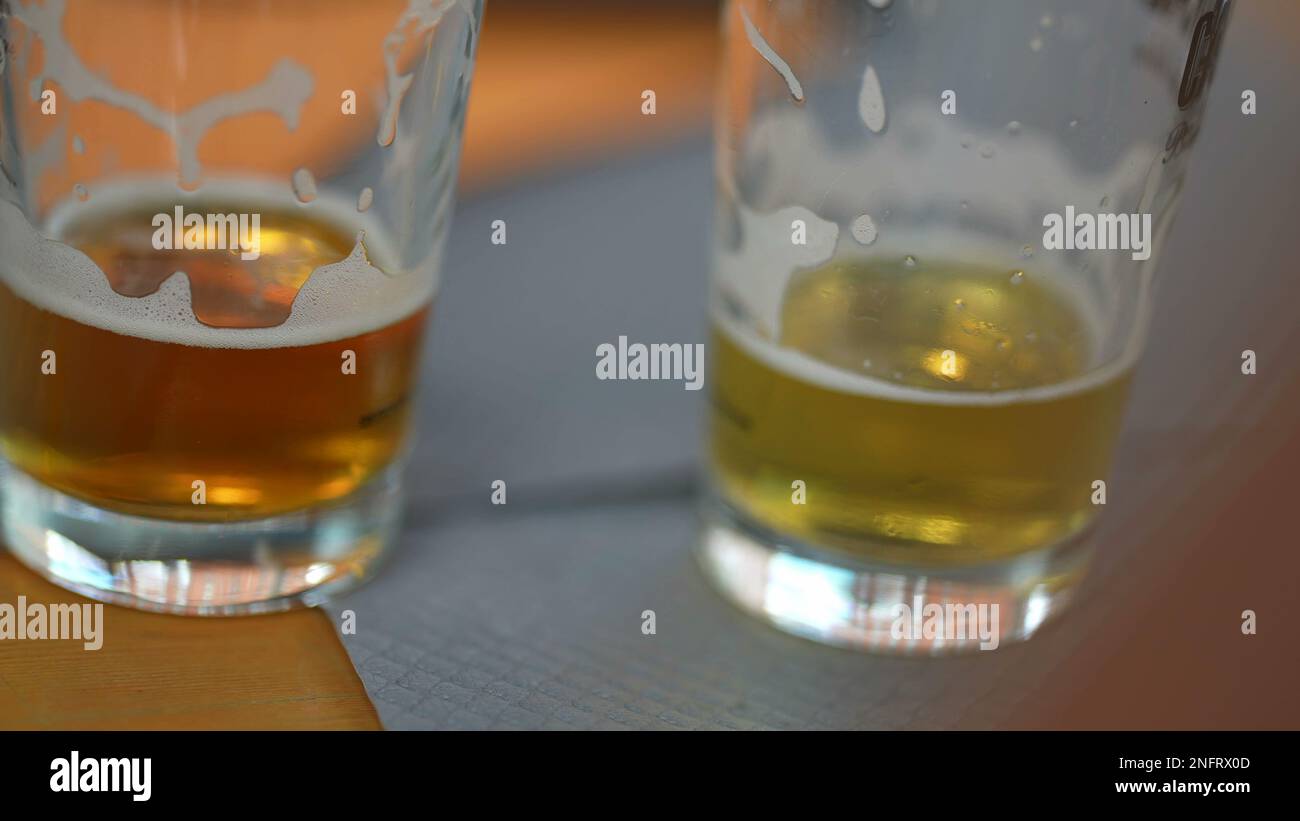 Two half empty draft beers at restaurant table. Person hand closeup ...