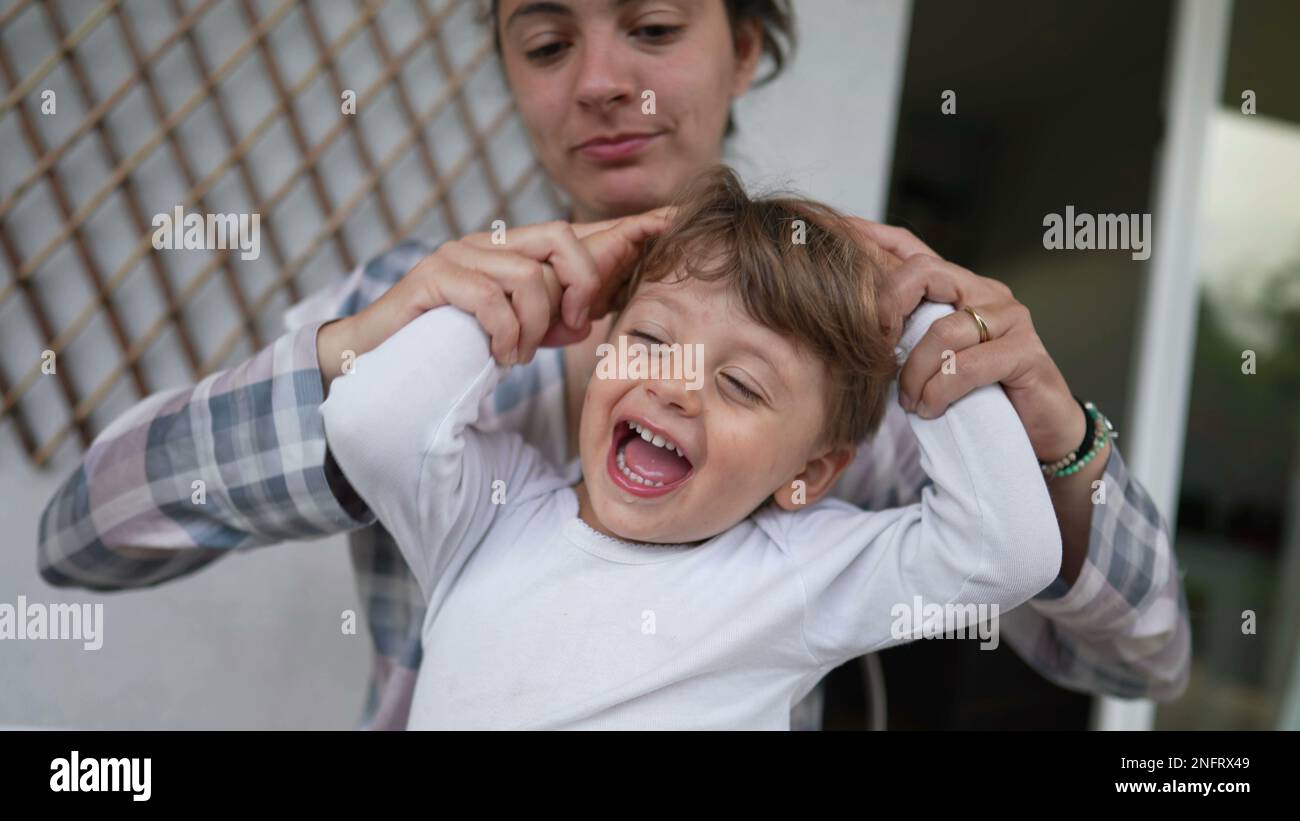 Playful mother and child together at home. Parent tapping son head with ...