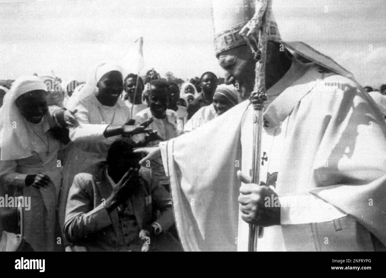 Pope John Paul II touches the head of a praying crippled man during a ...