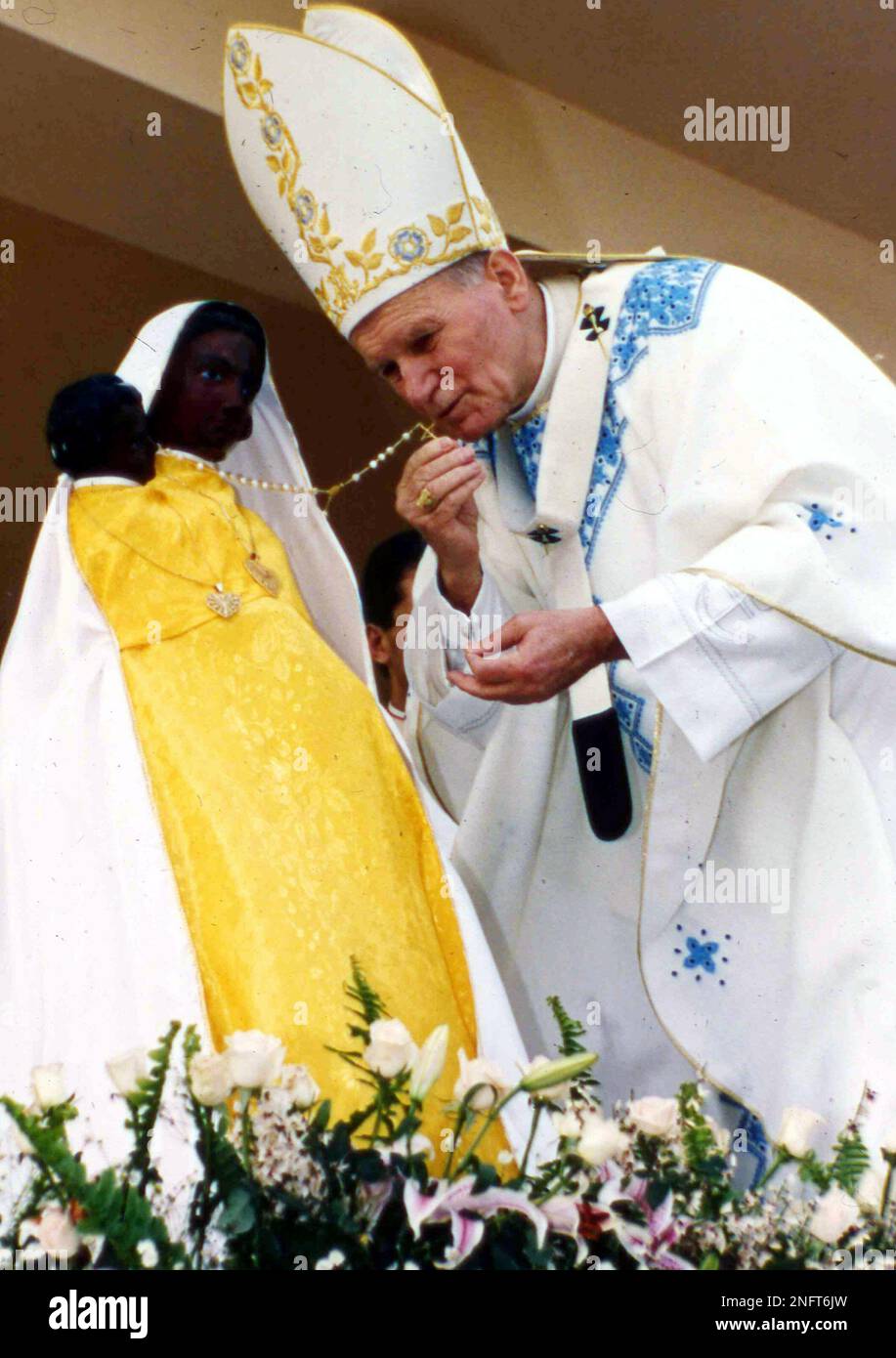 Pope John Paul II kisses a necklace that he has put around a statue of ...