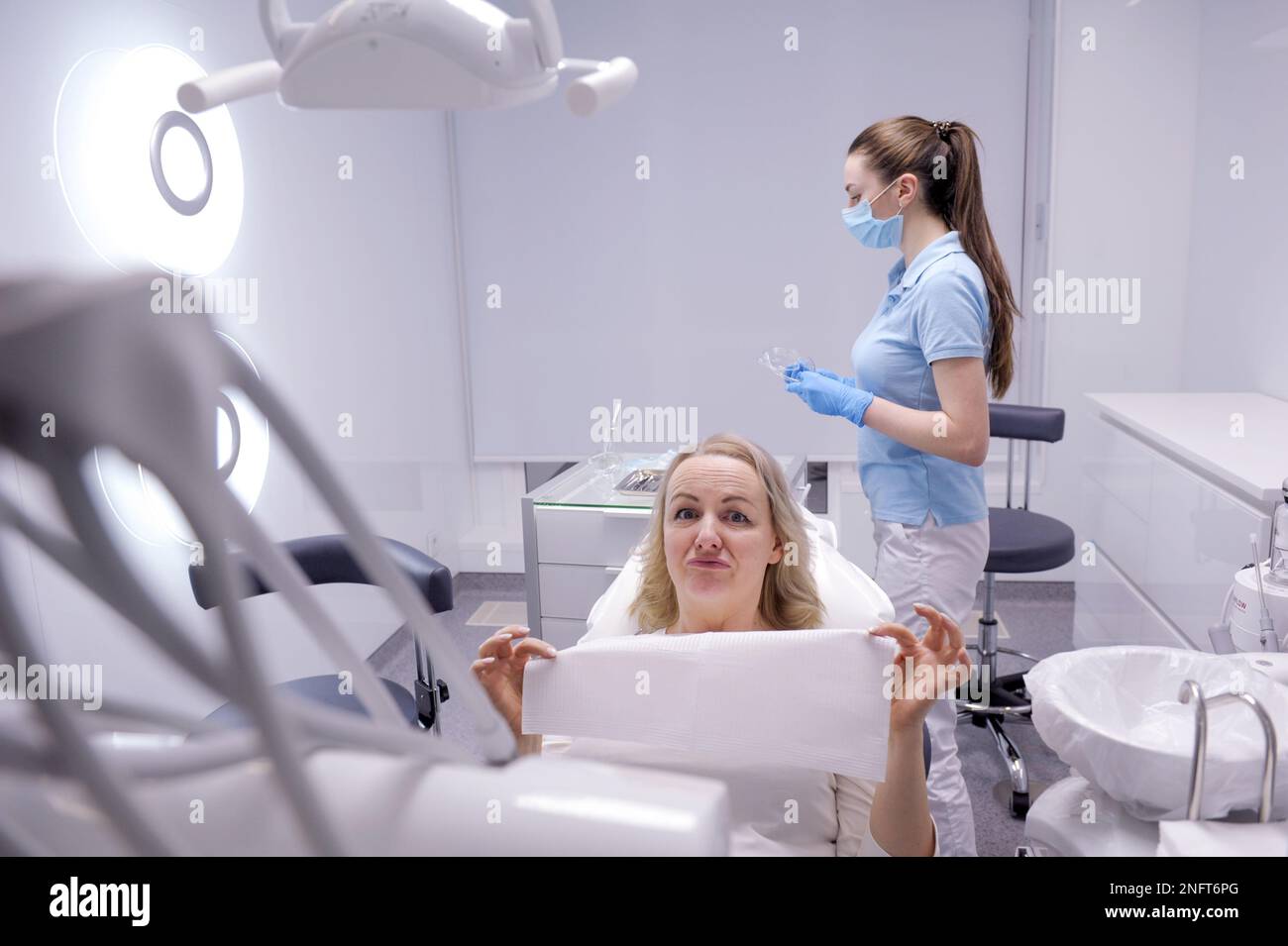 woman in dentistry is wearing dental bib for patient disposable napkin ...
