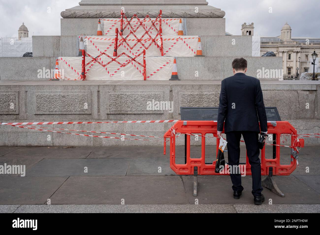 A member of the public admires Nelson's Column, beneath hazard tape ...