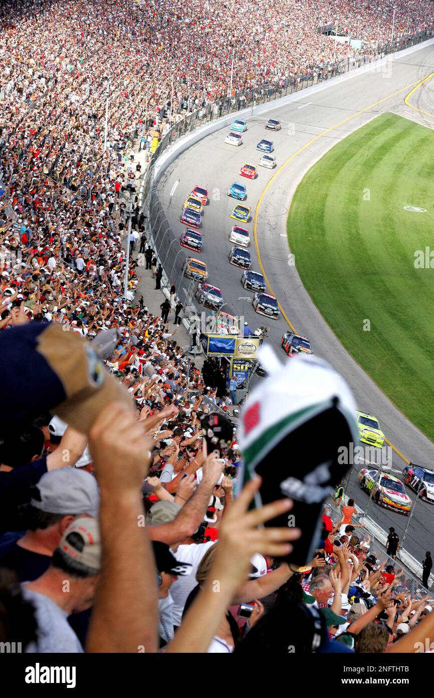 Fans watch cars race through the tri-oval at the Daytona International ...